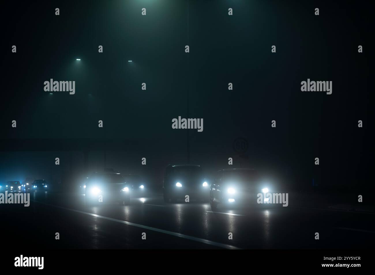 Vehicle headlights moving through thick fog on the highway at night ...