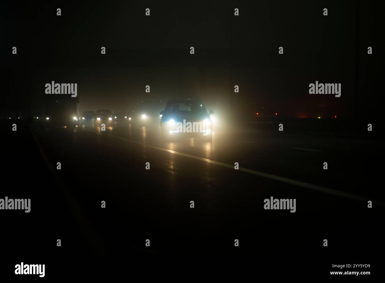 Vehicle headlights moving through thick fog on the highway at night ...