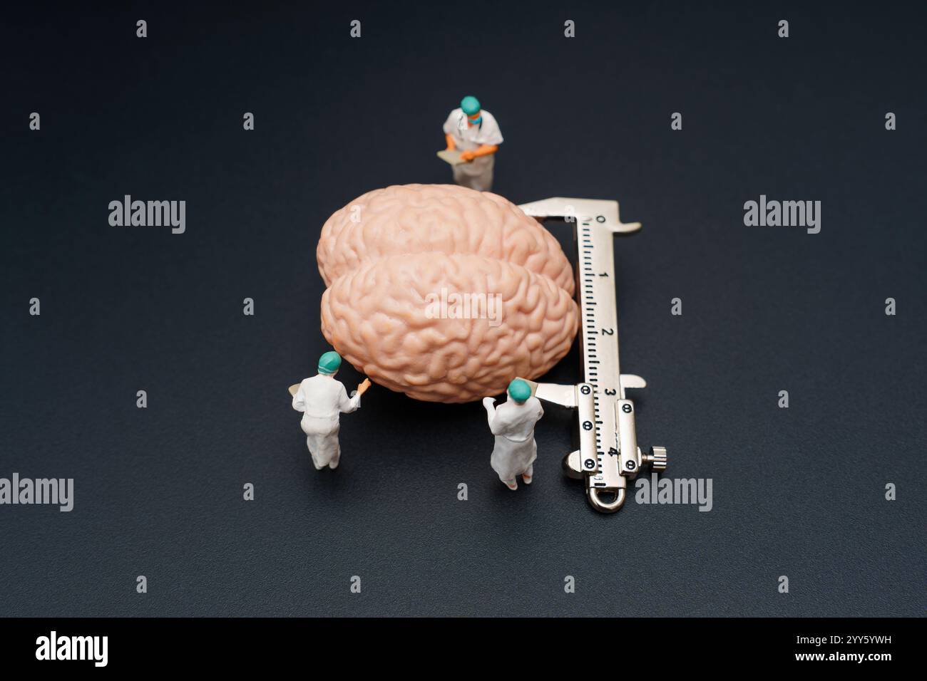 Detailed model of a human brain surrounded by miniature surgeon ...