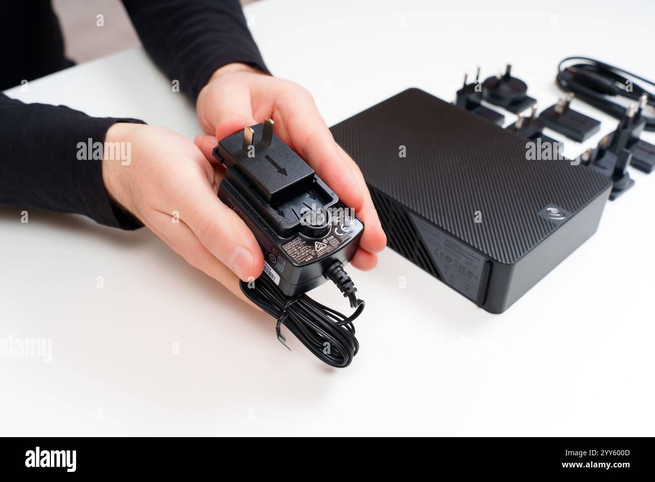 Kyiv, Ukraine - October 23, 2024: Hands holding the power adapter with ...