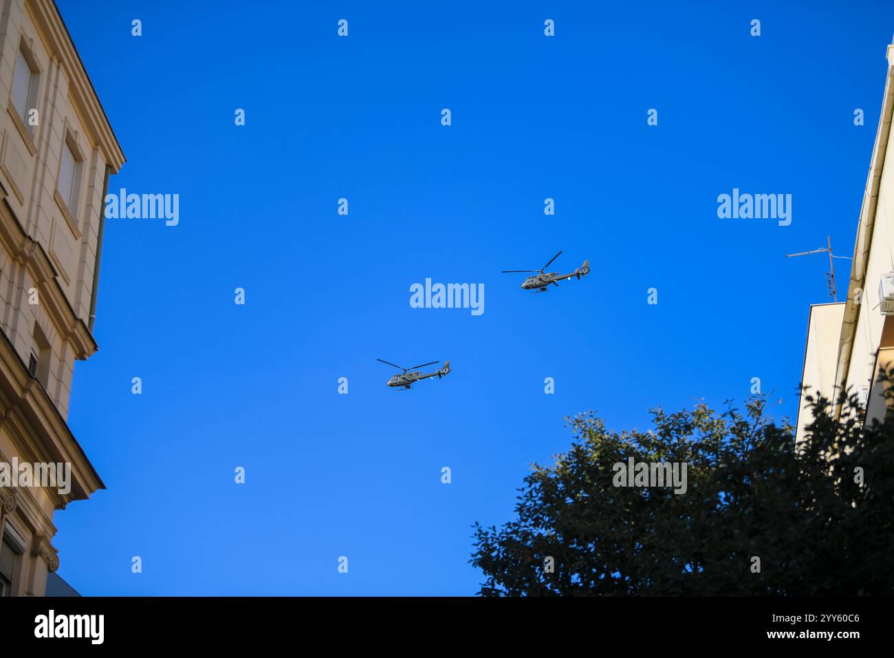 Two Military Helicopters flying in formation in city, between buildings ...