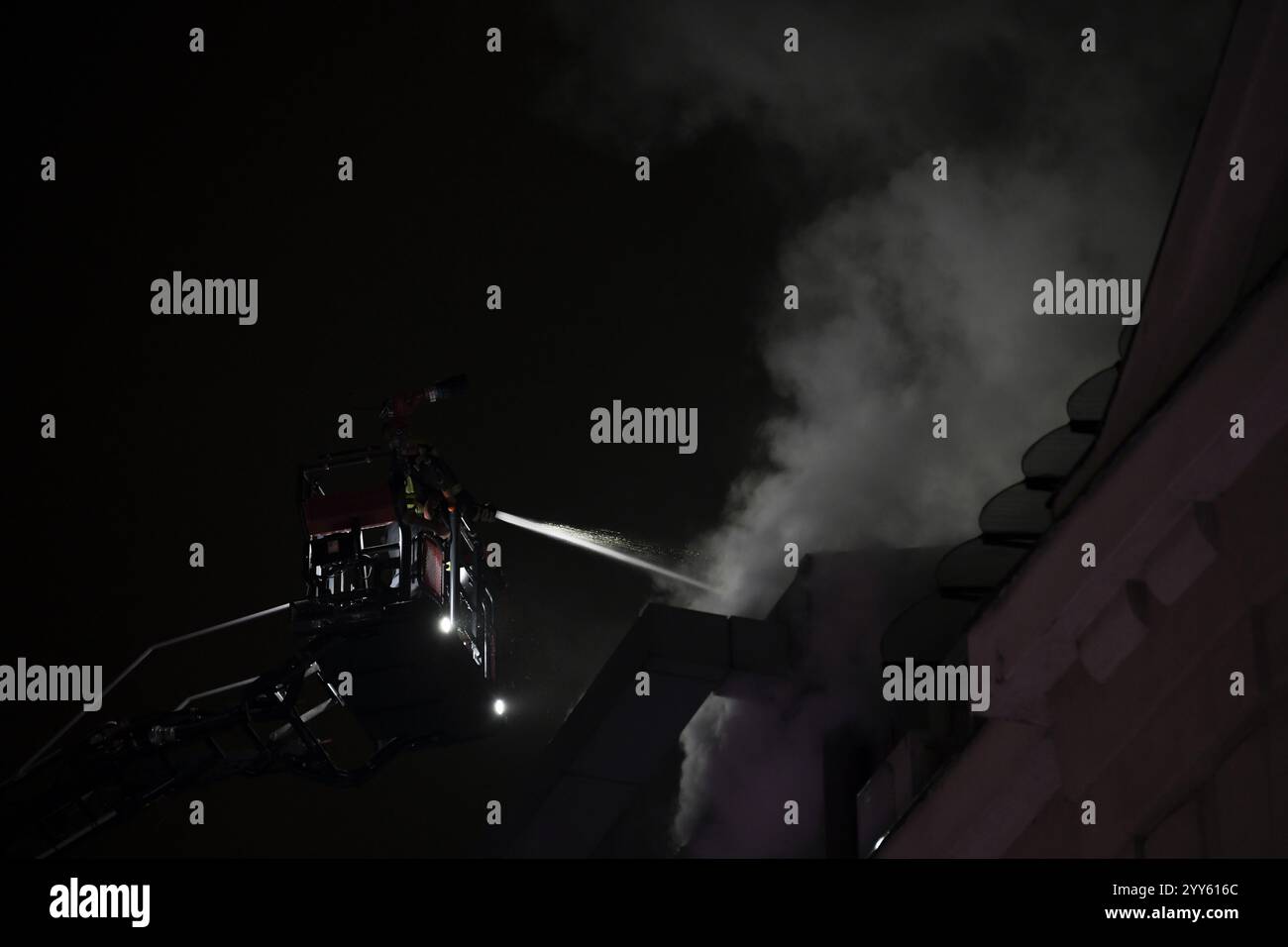 Firefighters rise on a mechanical sliding ladder to the epicenter of ...