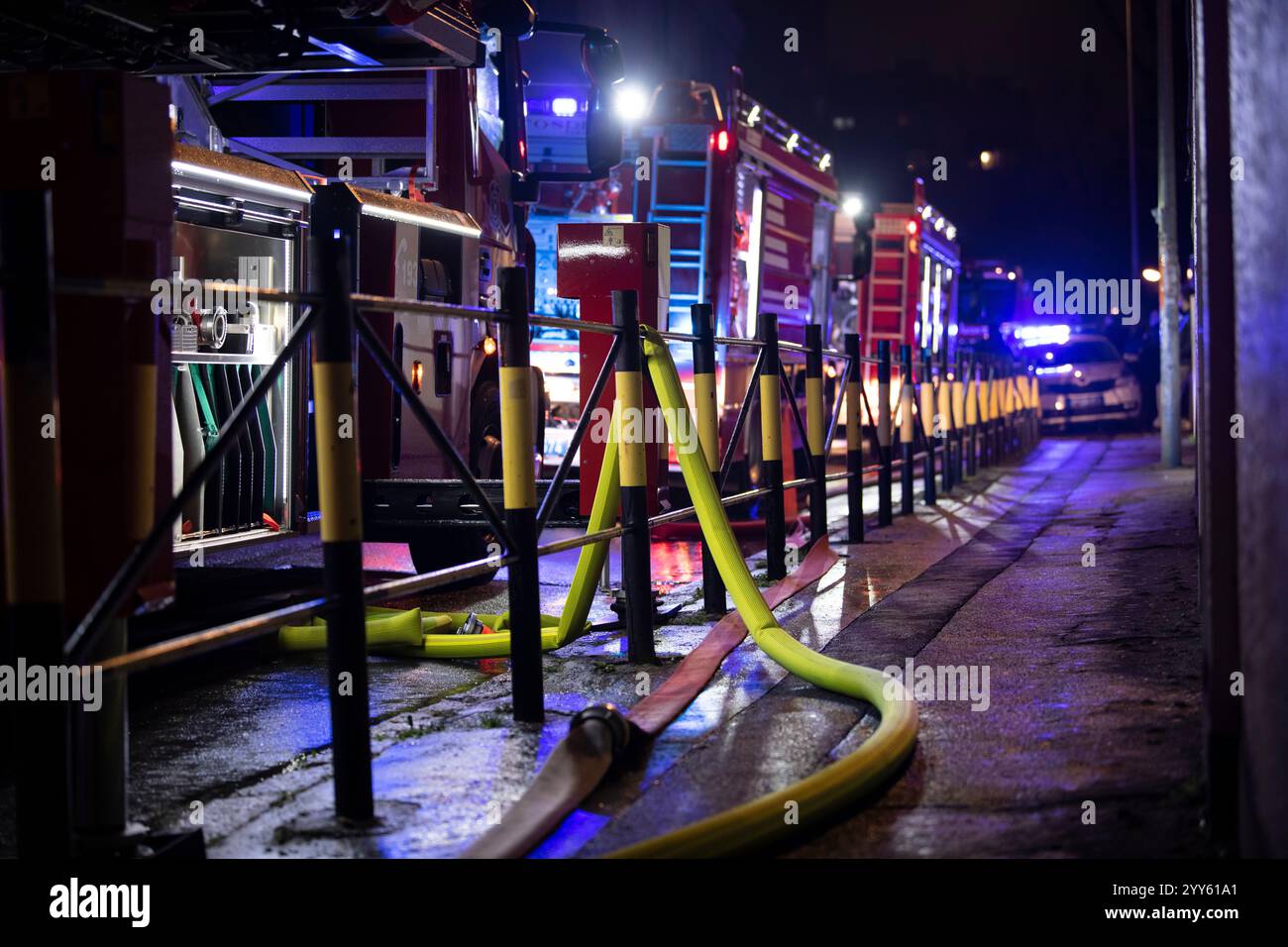 Fire Brigade in action. Close up of yellow fire hose with fire truck ...