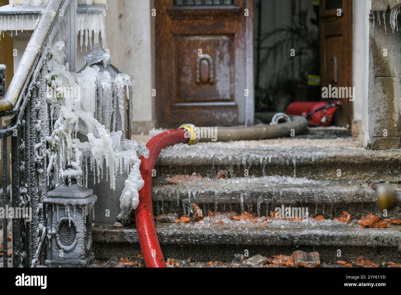 A cracked fire hose leaks water creating ice and icicles around stairs ...