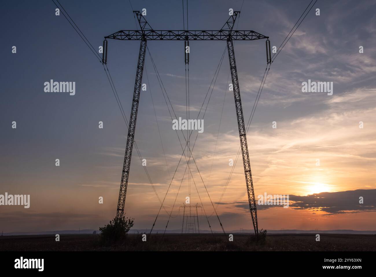 Silhouette of High voltage transmission lines and towers runing trough ...
