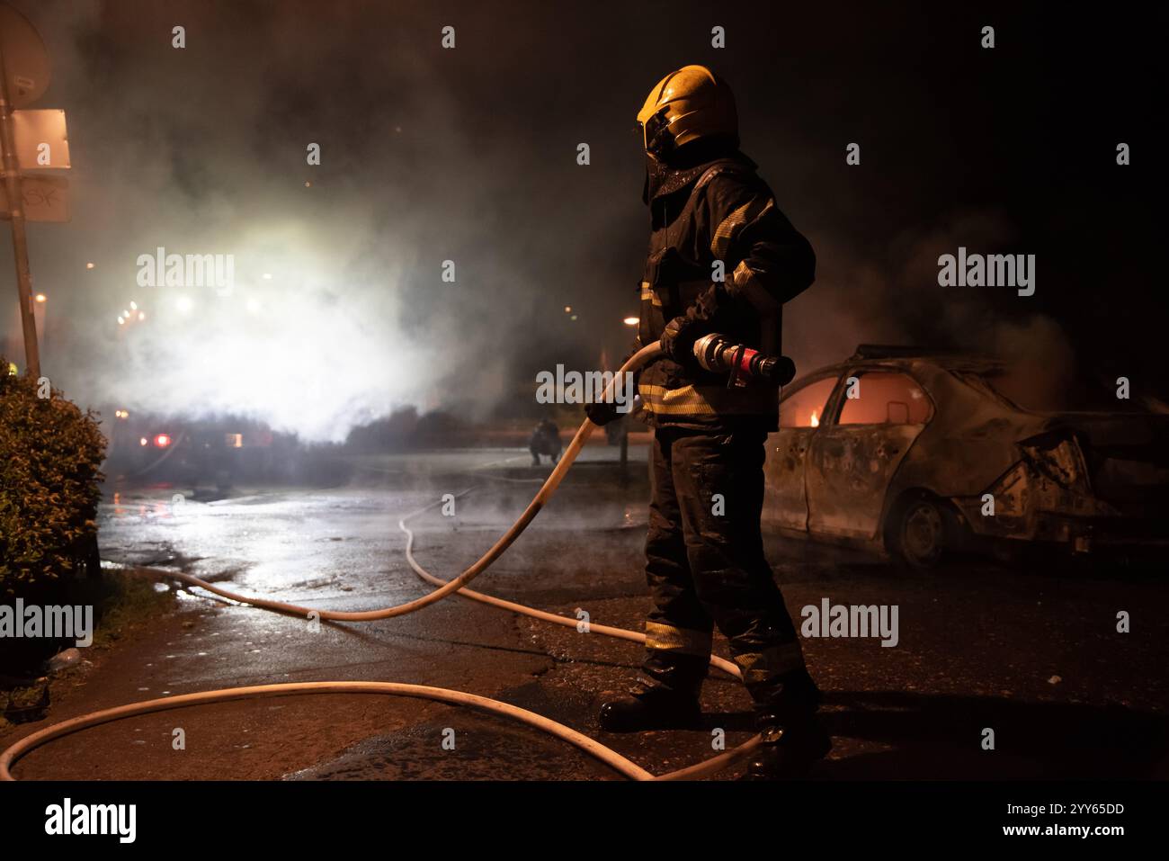 Firefighter trying to put down fire on burning police car in the center ...