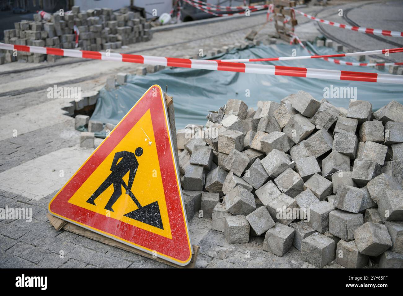 Construction zone or roadworks warning sign ahead of many small pellet with granite block ...