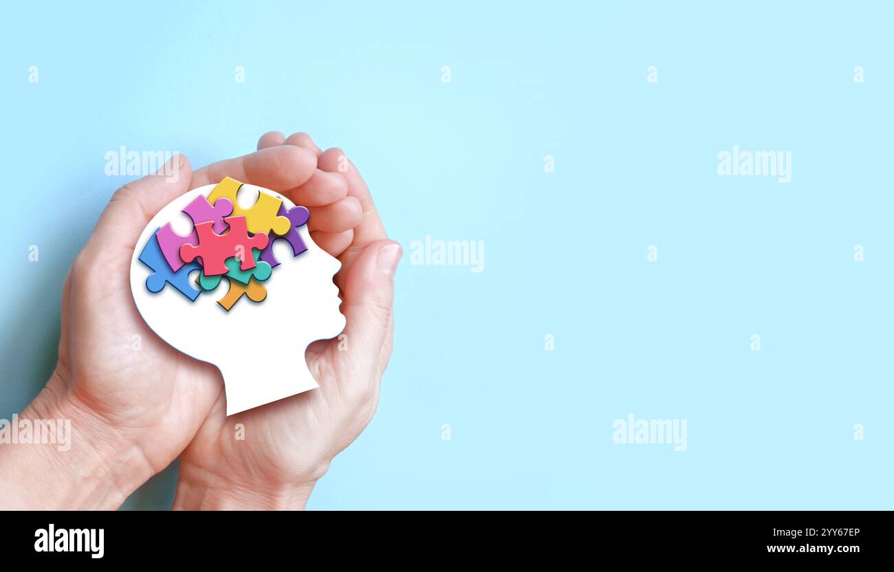 Hands holding paper head with jigsaw puzzle, Autism spectrum disorder ...