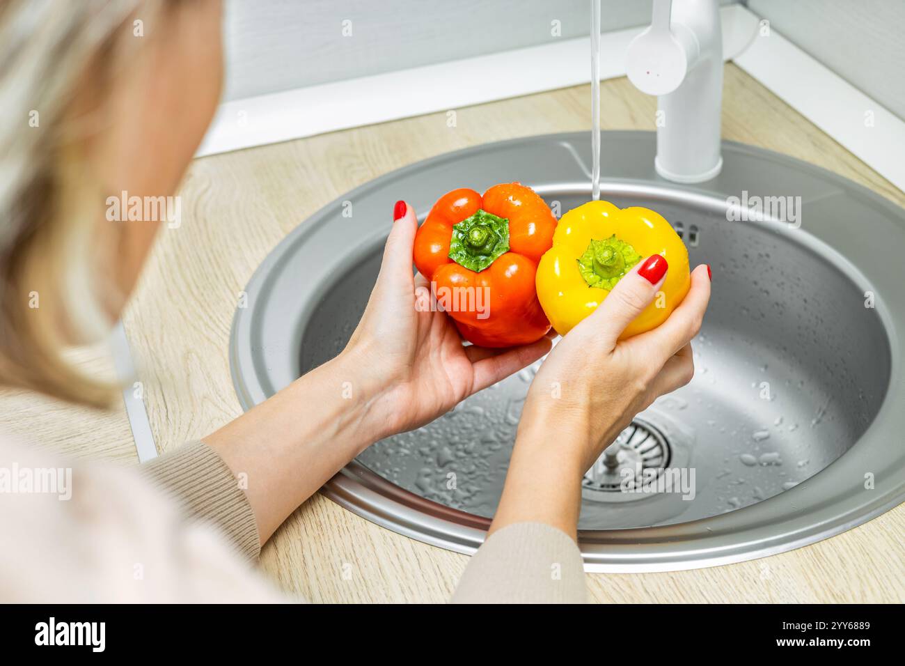 woman washing bell peppers in kitchen sink Stock Photo - Alamy