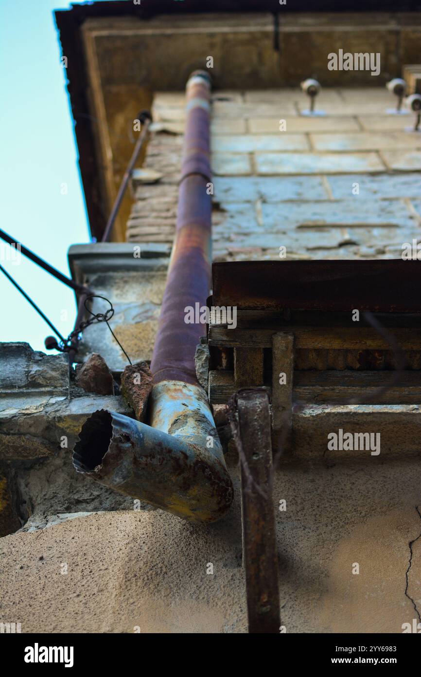 Closeup of a rusted old vintage roof rain gutter pipe, on old damaged ...