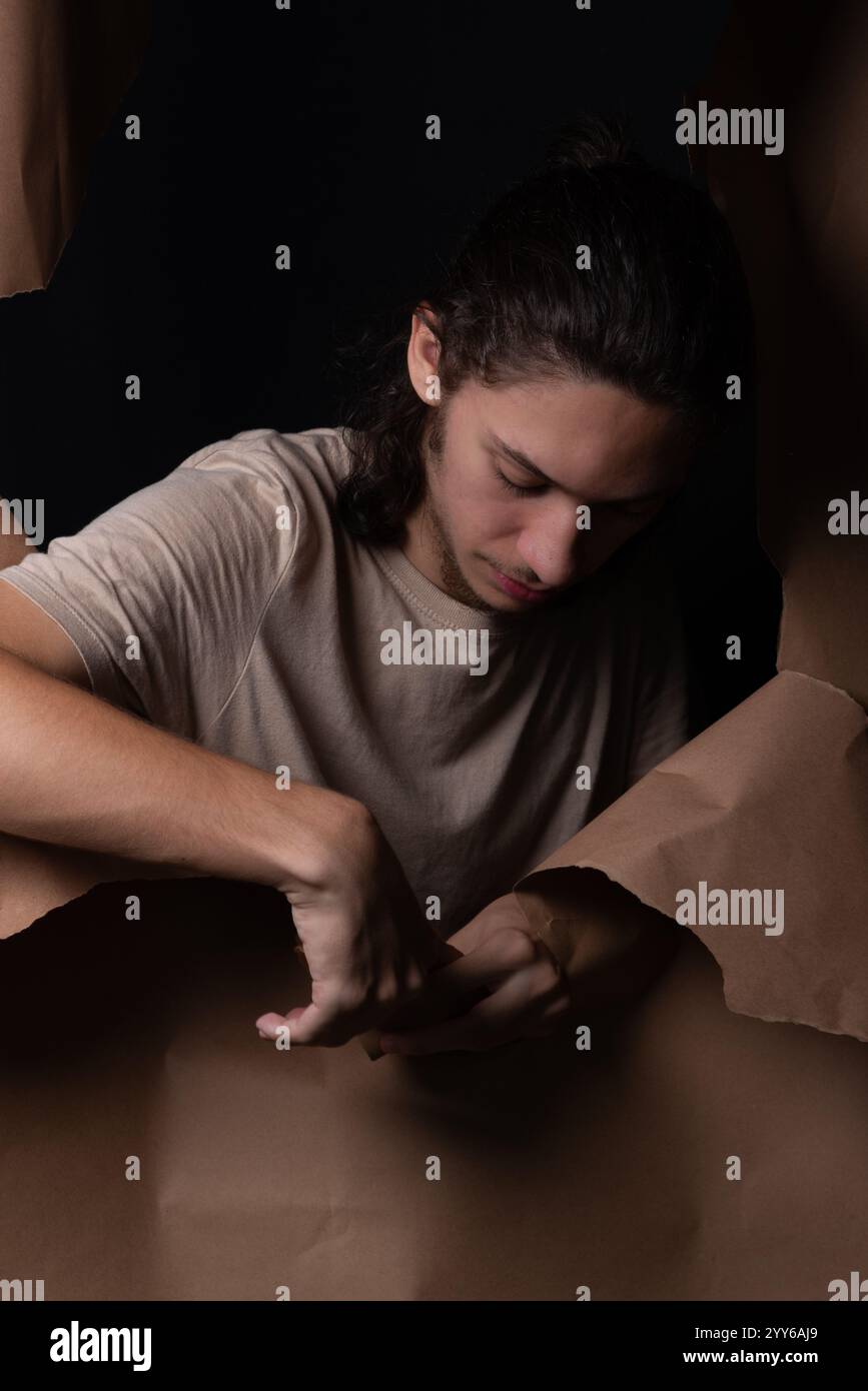 A man peering through a hole in a sheet of brown paper. Tearing the ...