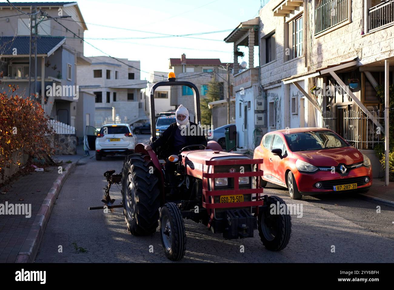 A man drives his tractor along the street in the town of Masada ...