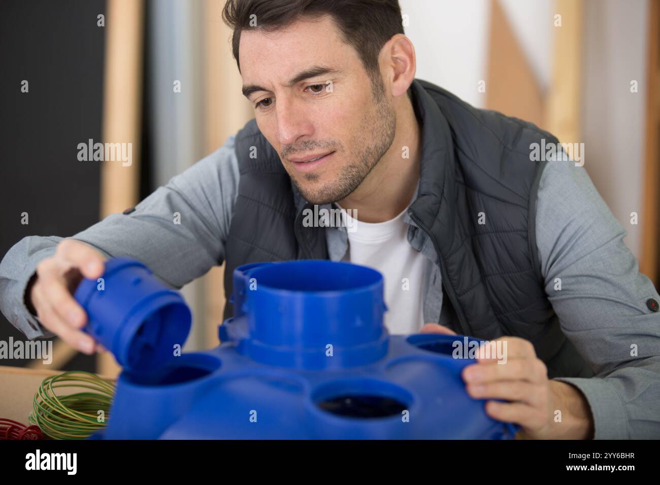 man assembling plastic electrical junction-box Stock Photo - Alamy