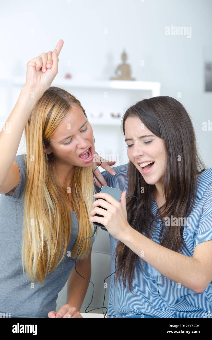 two female friends singing along to music on smartphone Stock Photo - Alamy
