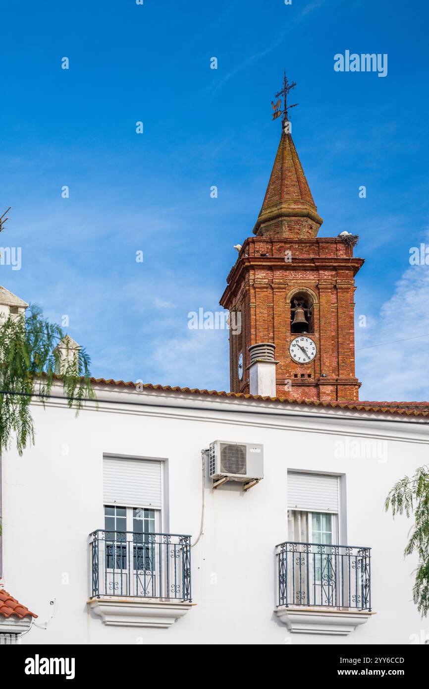 Old brick bell tower with clock and white architecture under a clear ...