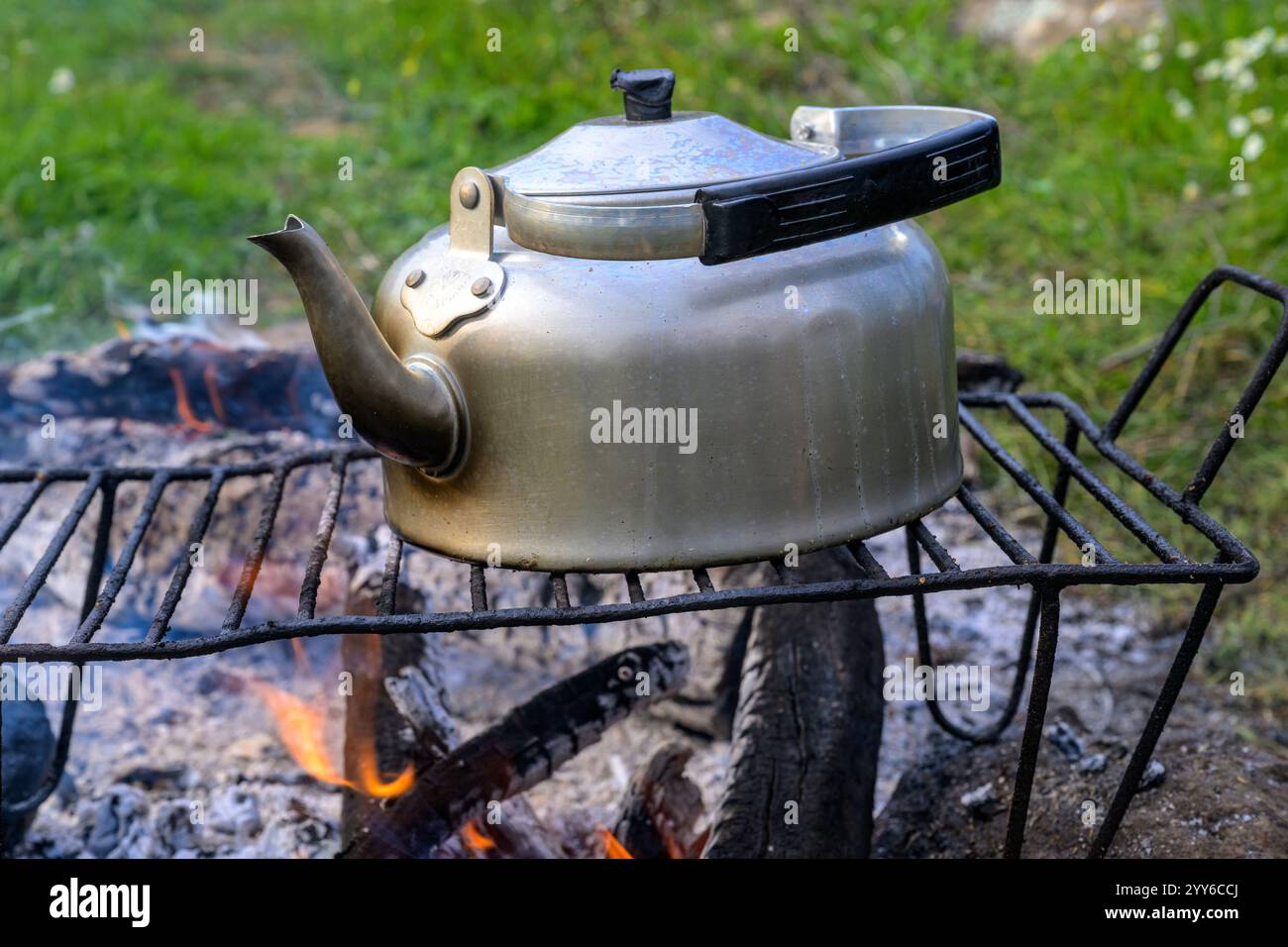Kettle placed on a grill over a campfire, representing outdoor cooking ...