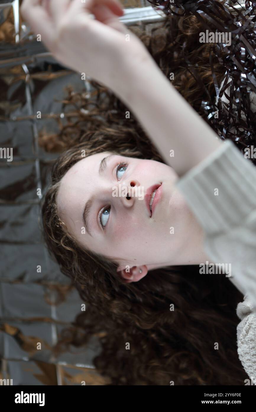 Teenage girl lying on silver background with cassette tape tangled ...