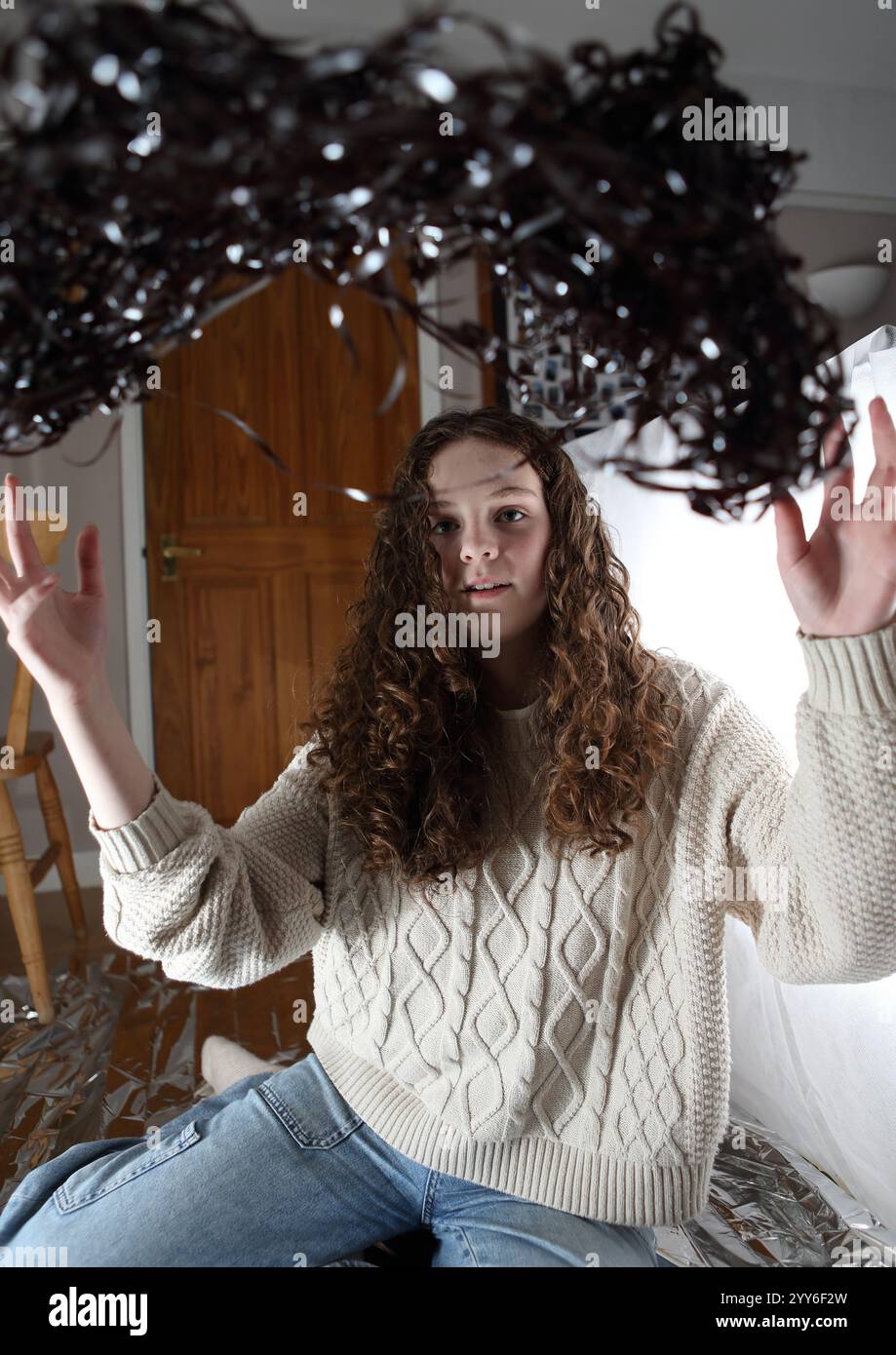 Teenage girl tossing up twisted unwound cassette tape into the air ...