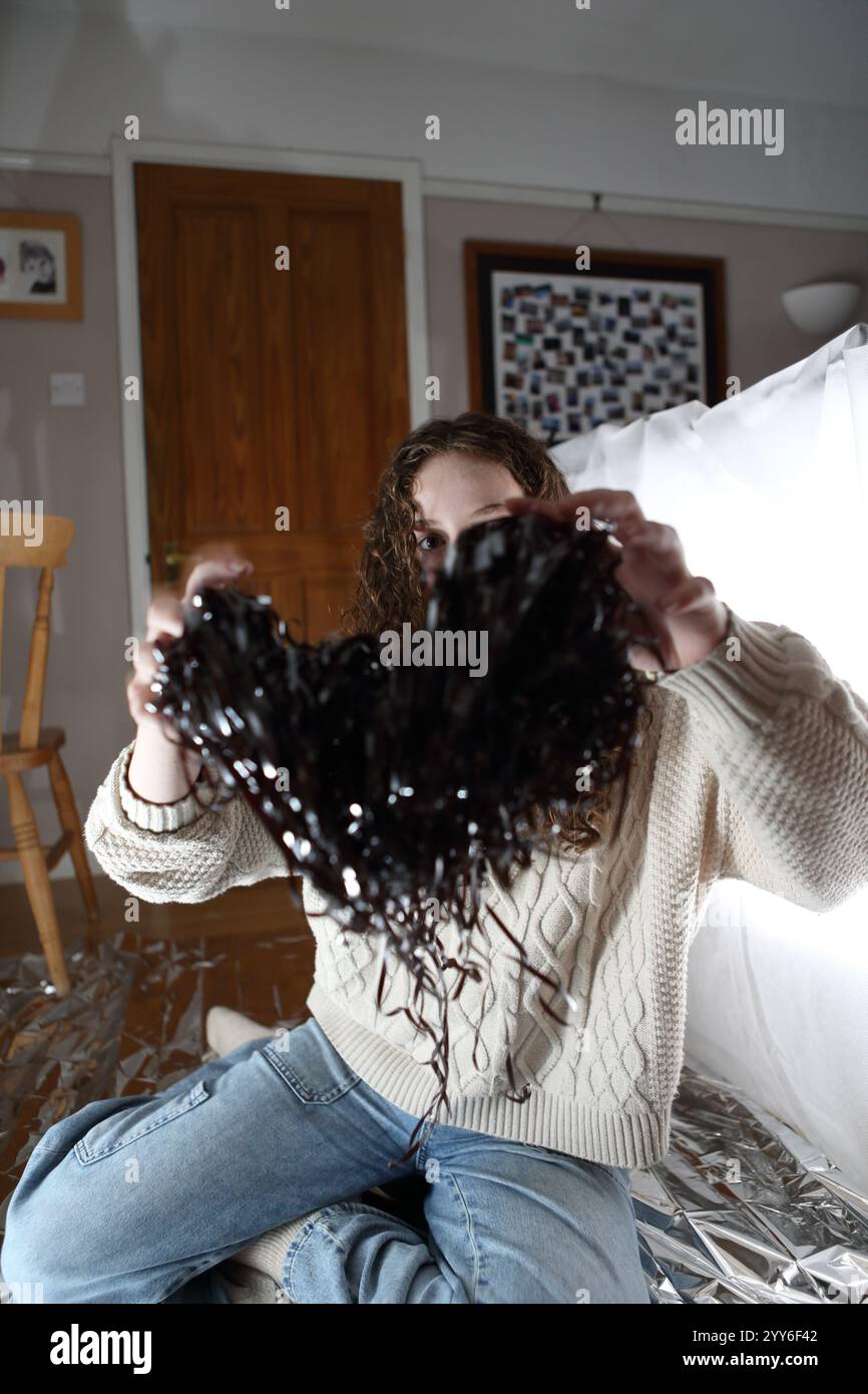 Teenage girl tossing up twisted unwound cassette tape into the air ...