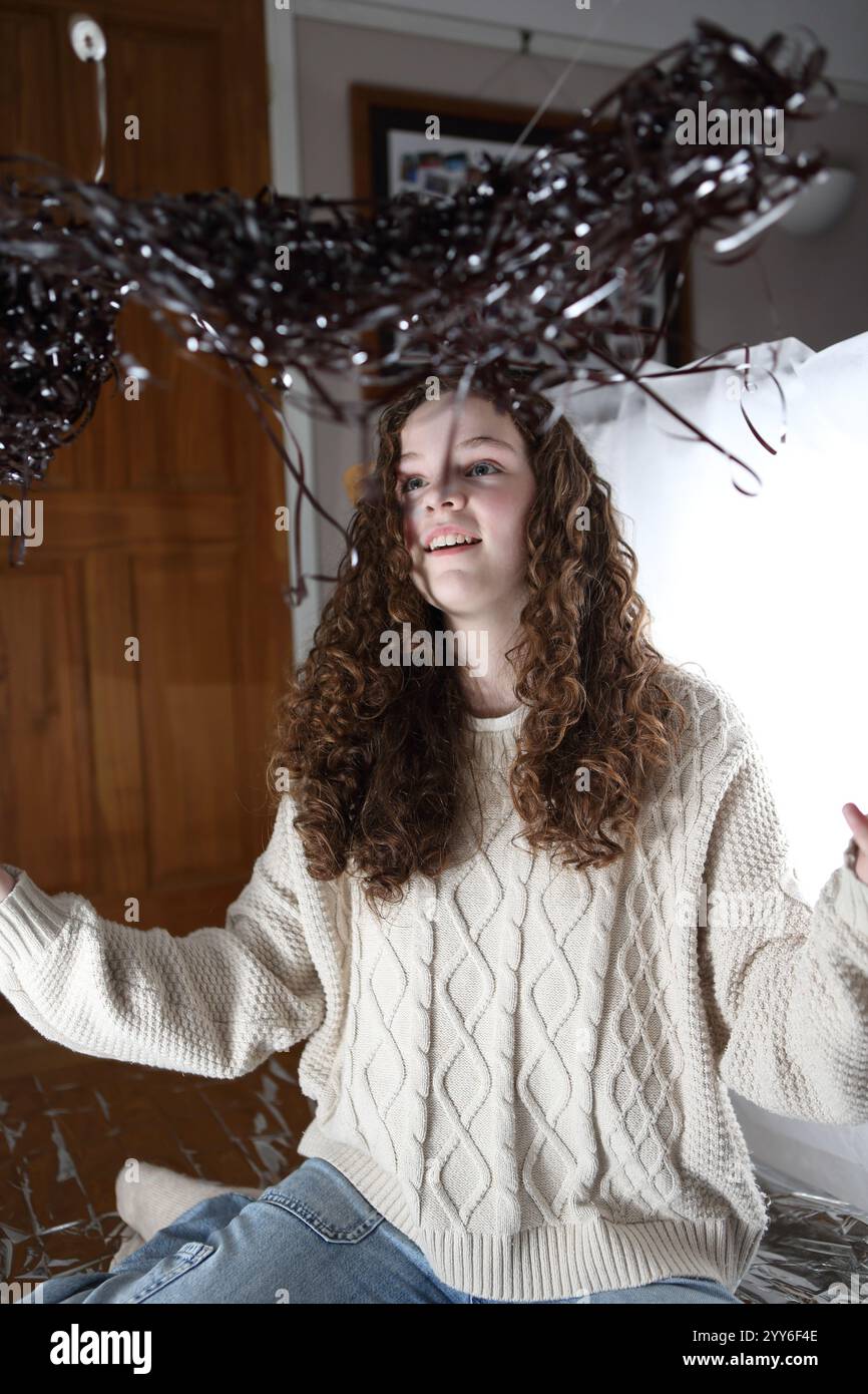 Teenage girl tossing up twisted unwound cassette tape into the air ...