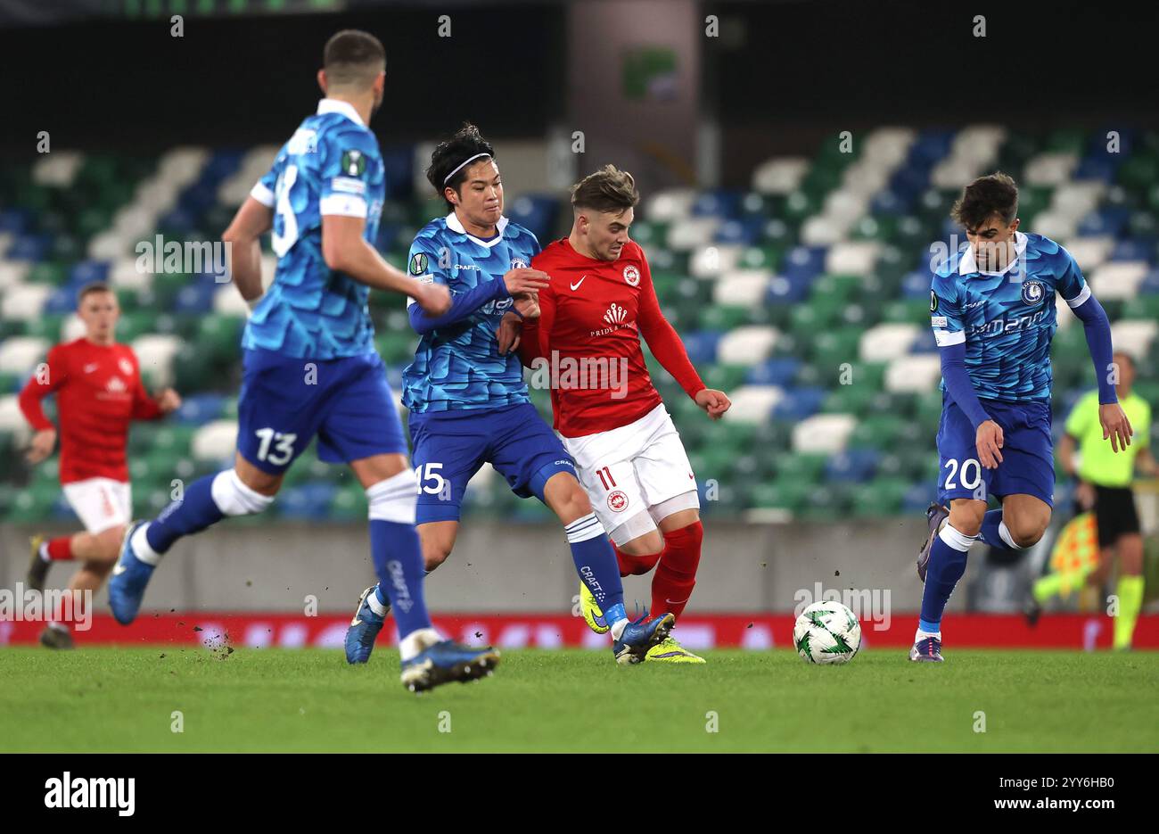 Larne's Sean Graham (centre) battles for the ball with Gent's Atsuki ...