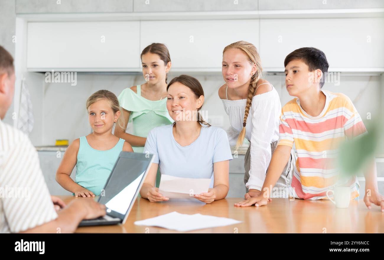 Man is typing on laptop and listening to joyful wife read aloud letter ...
