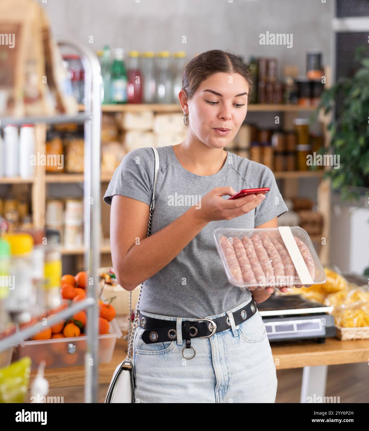 Girl shopper scanning QR code on raw sausages label in grocery ...
