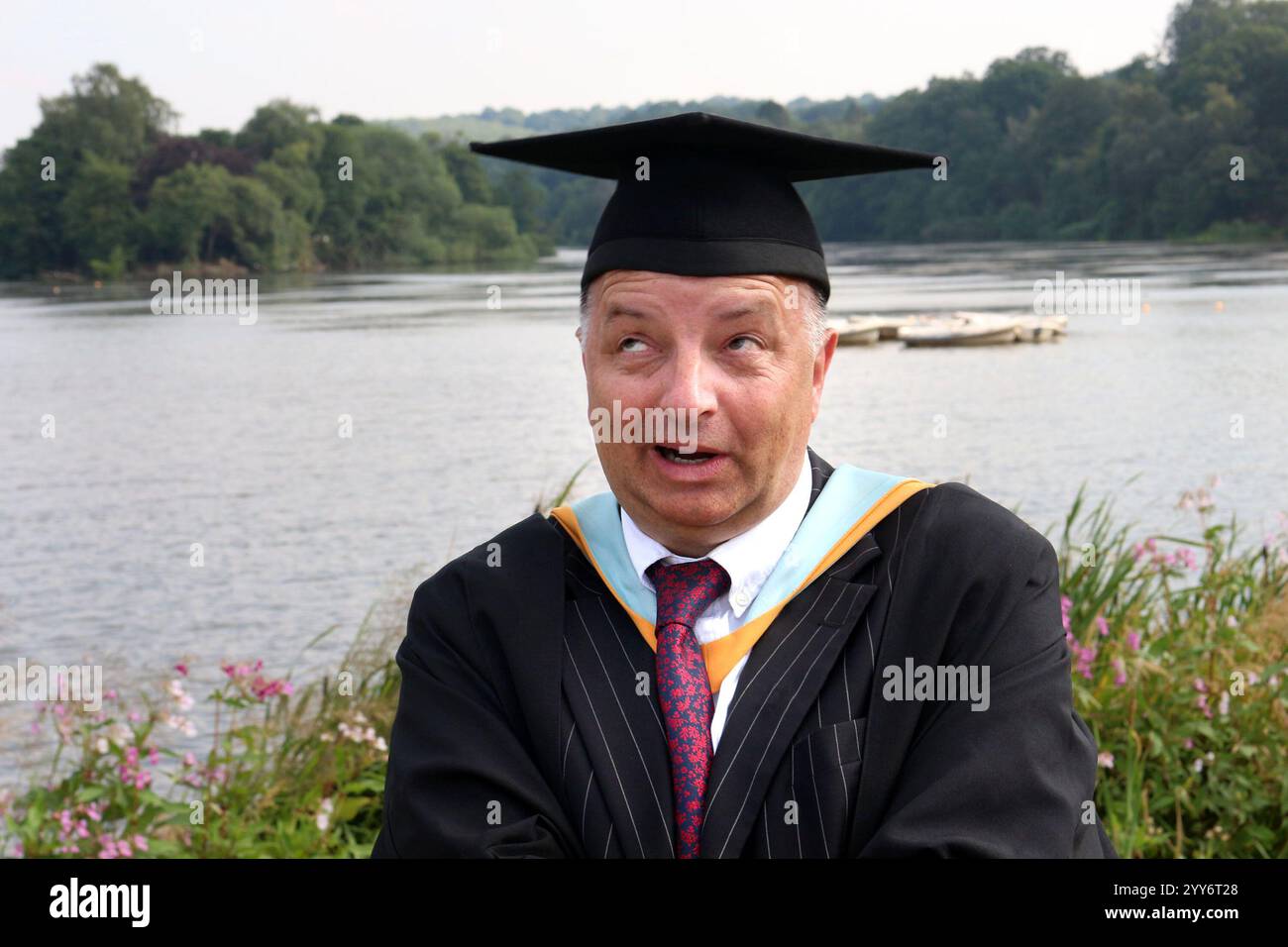 Senior man with a humourous goofy expression wearing a graduation cap ...