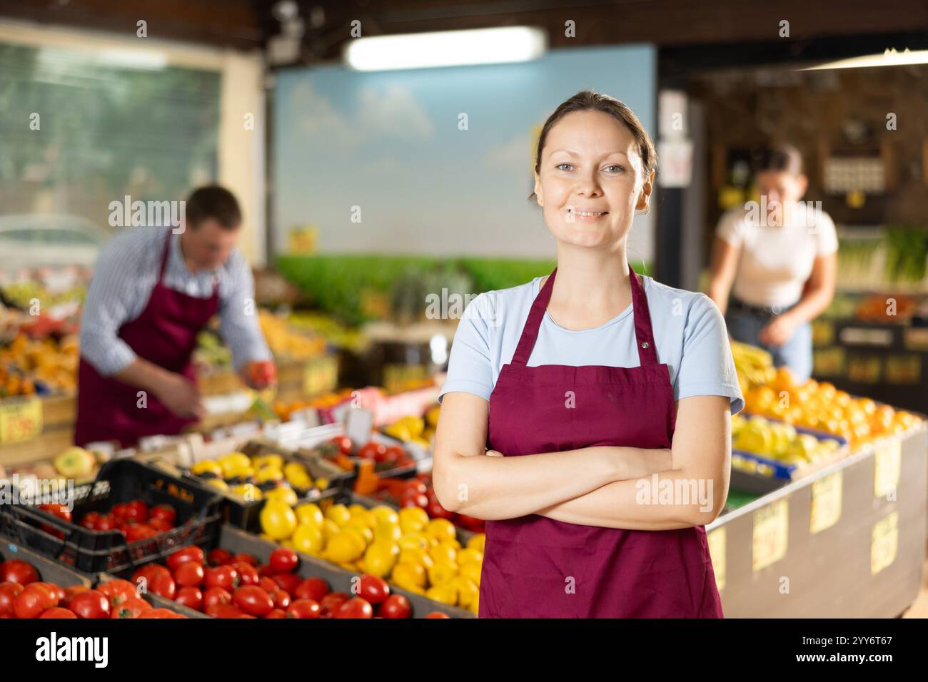 Positive and friendly store woman employee stands with arms crossed on ...