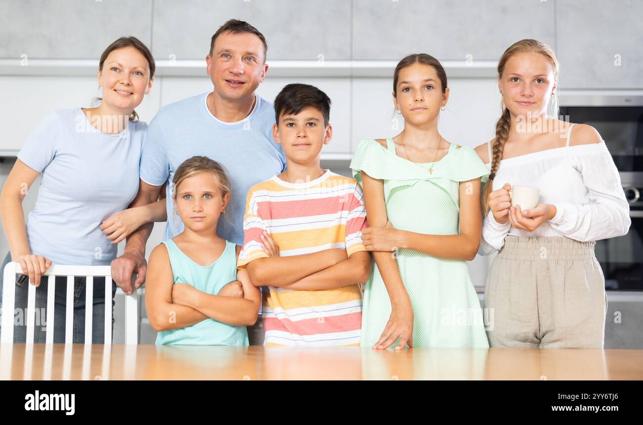 Happy dad and mum with three daughters and son is standing near kitchen ...