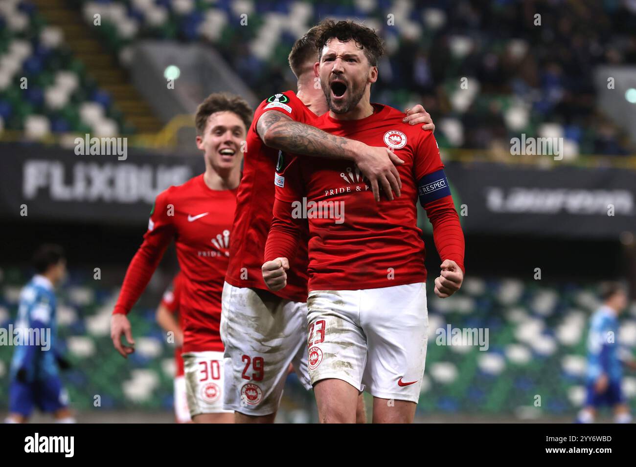 Larne's Tomas Cosgrove (right) celebrates scoring their side's first ...