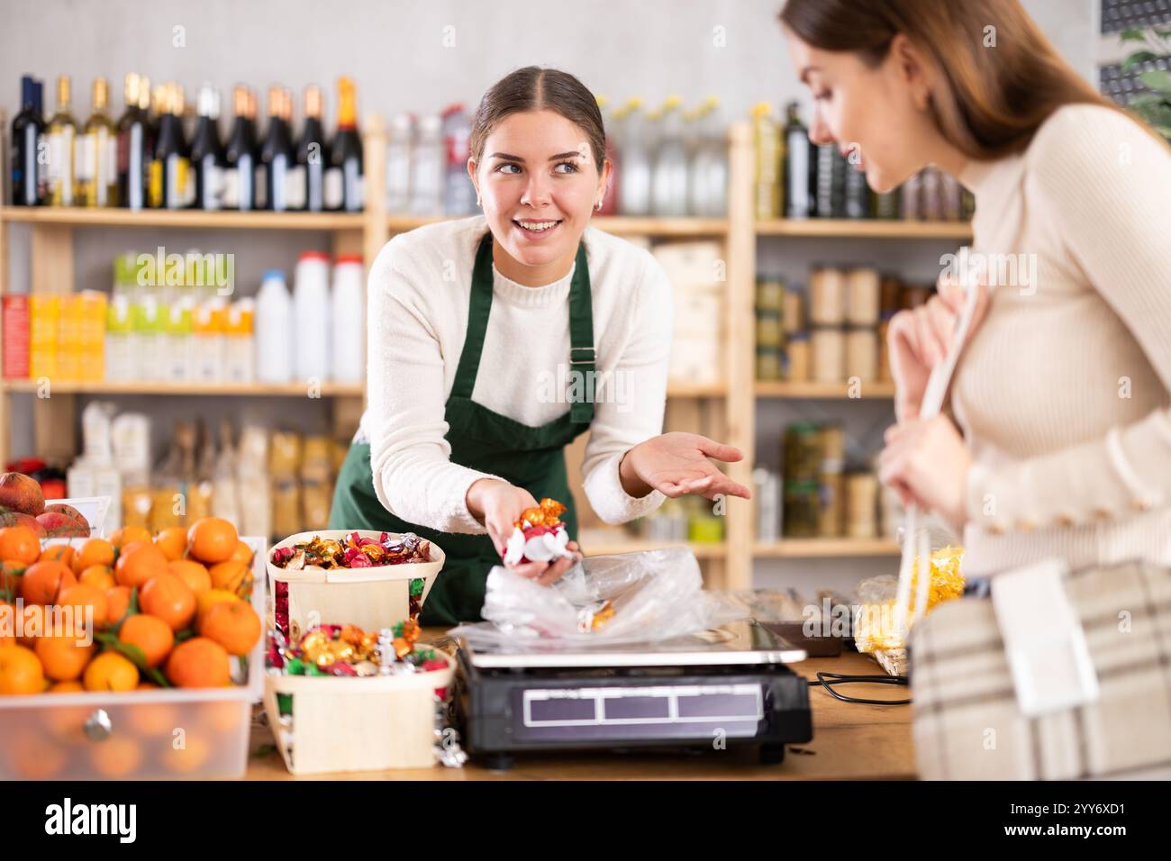 Female vendor weighs candies on scales and sells candies to customer ...
