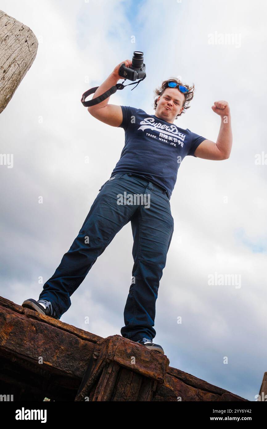 young Man standing confidently in strongman pose on a wooden structure ...