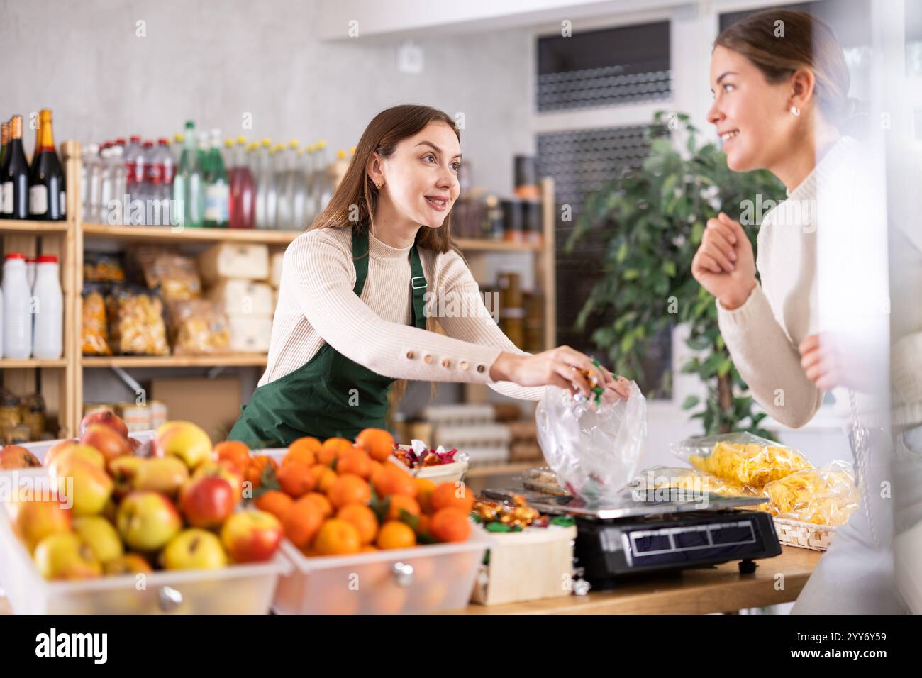 Female vendor weighs candies on scales and sells candies to customer ...