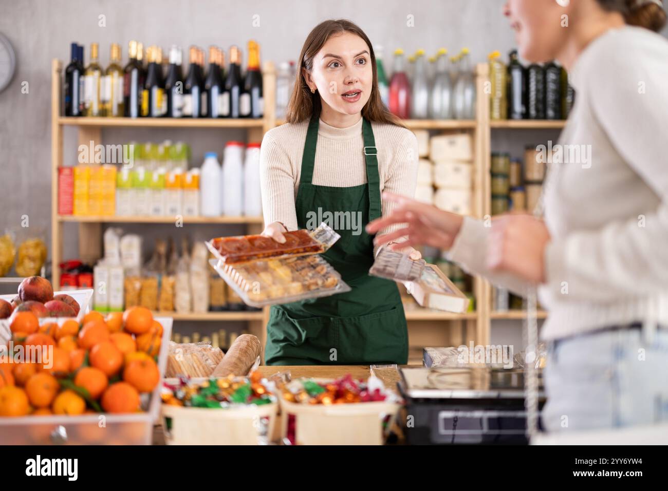 Woman store employee offers customer to choose sweets, shows packed ...