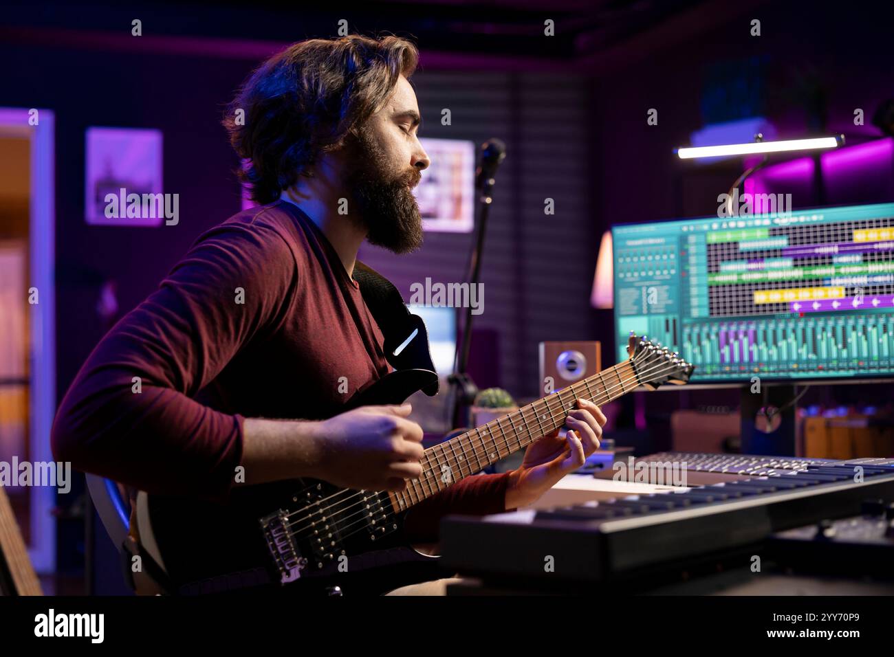 Musical performer playing guitar and recording his new tunes in home studio, using professional ...