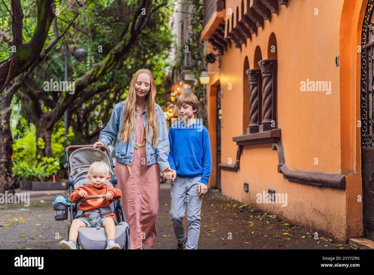 Mother with her two sons exploring lush streets of Condesa, Mexico City. Family adventure in a ...