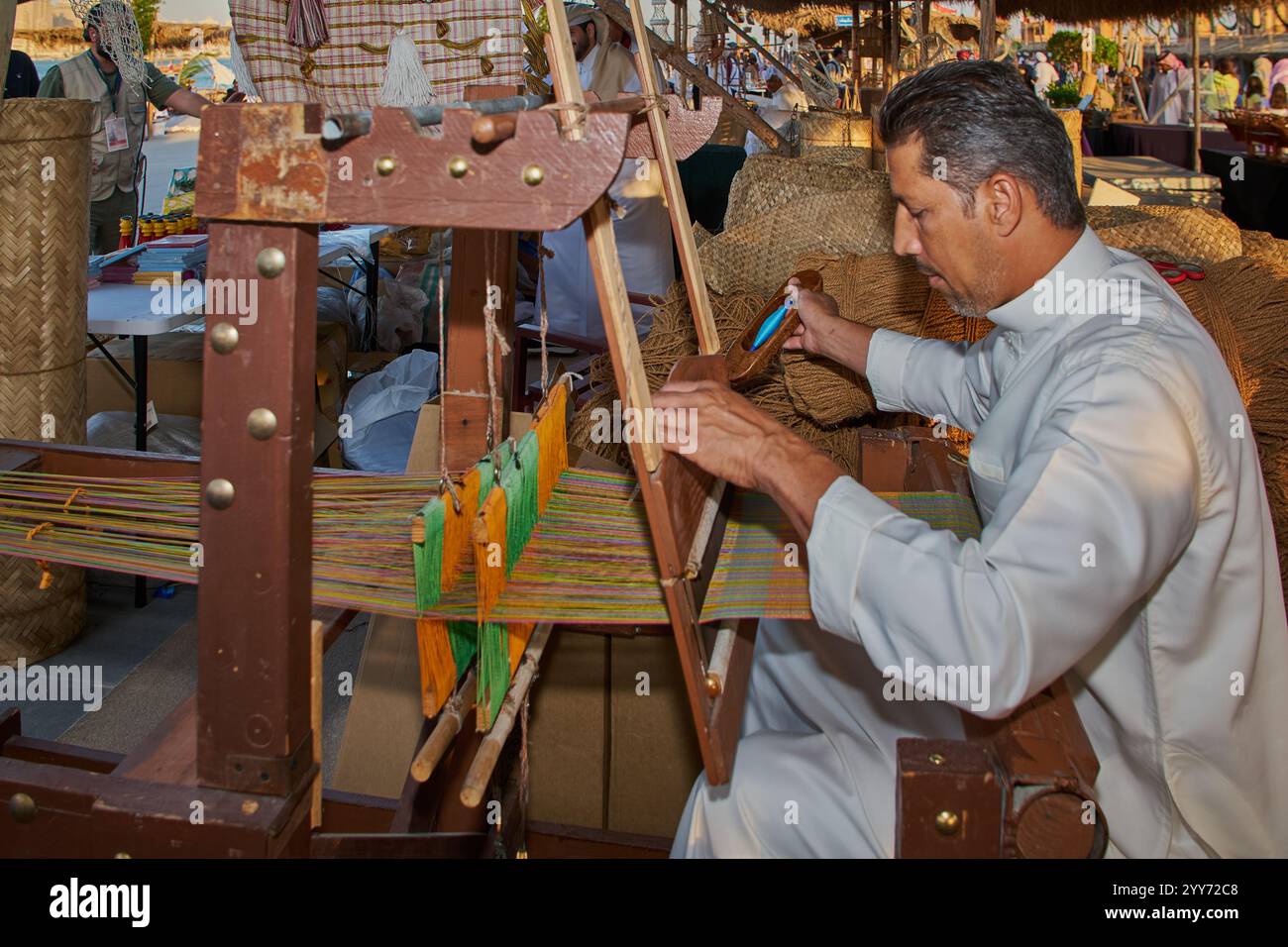 An Arabic craftsman working on traditional wooden loom weaving with ...