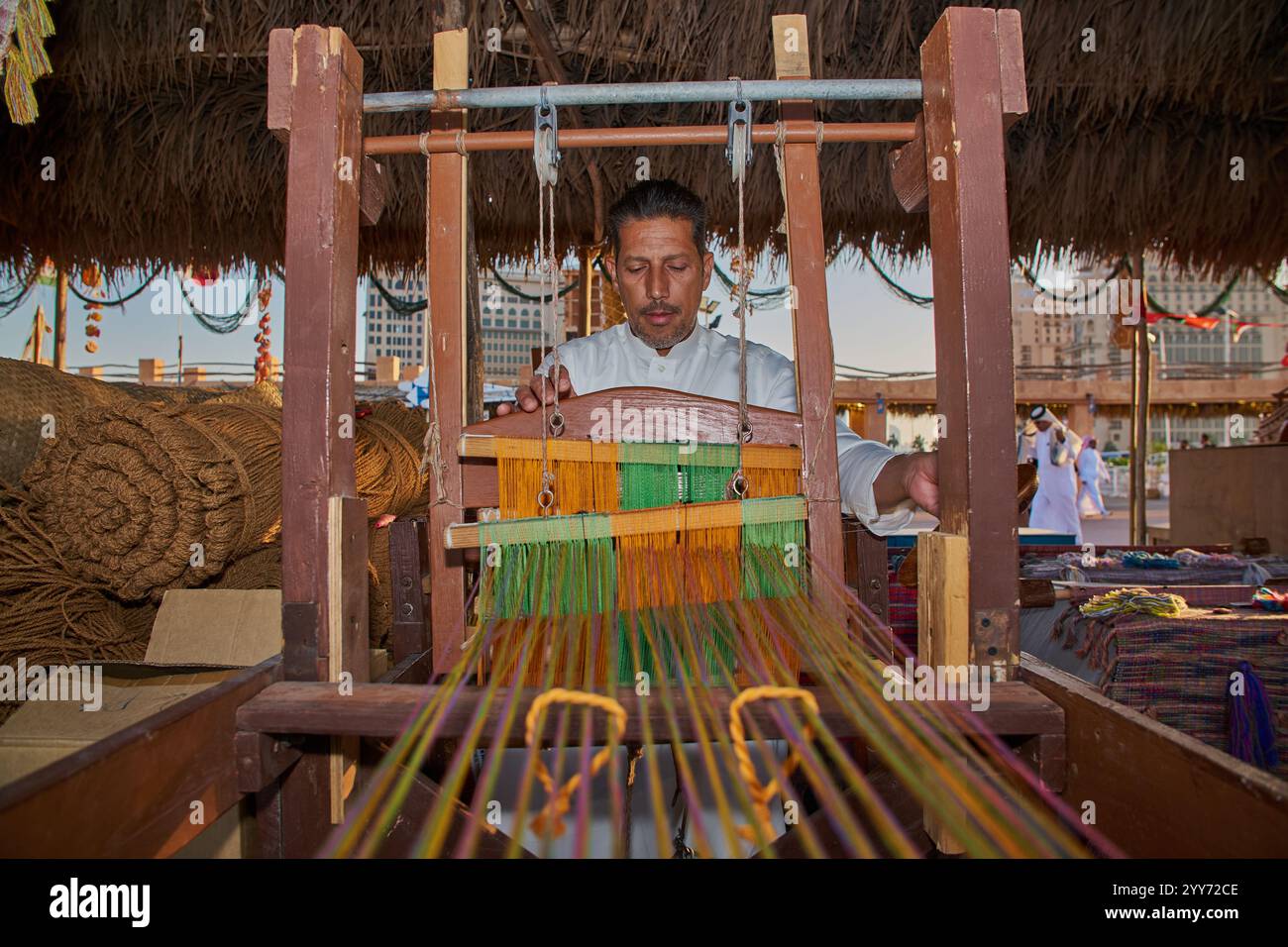 An Arabic craftsman working on traditional wooden loom weaving with ...