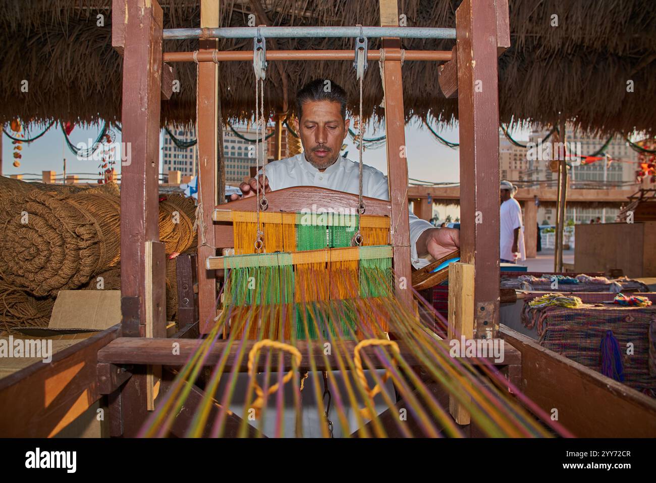 An Arabic craftsman working on traditional wooden loom weaving with colored threads during ...