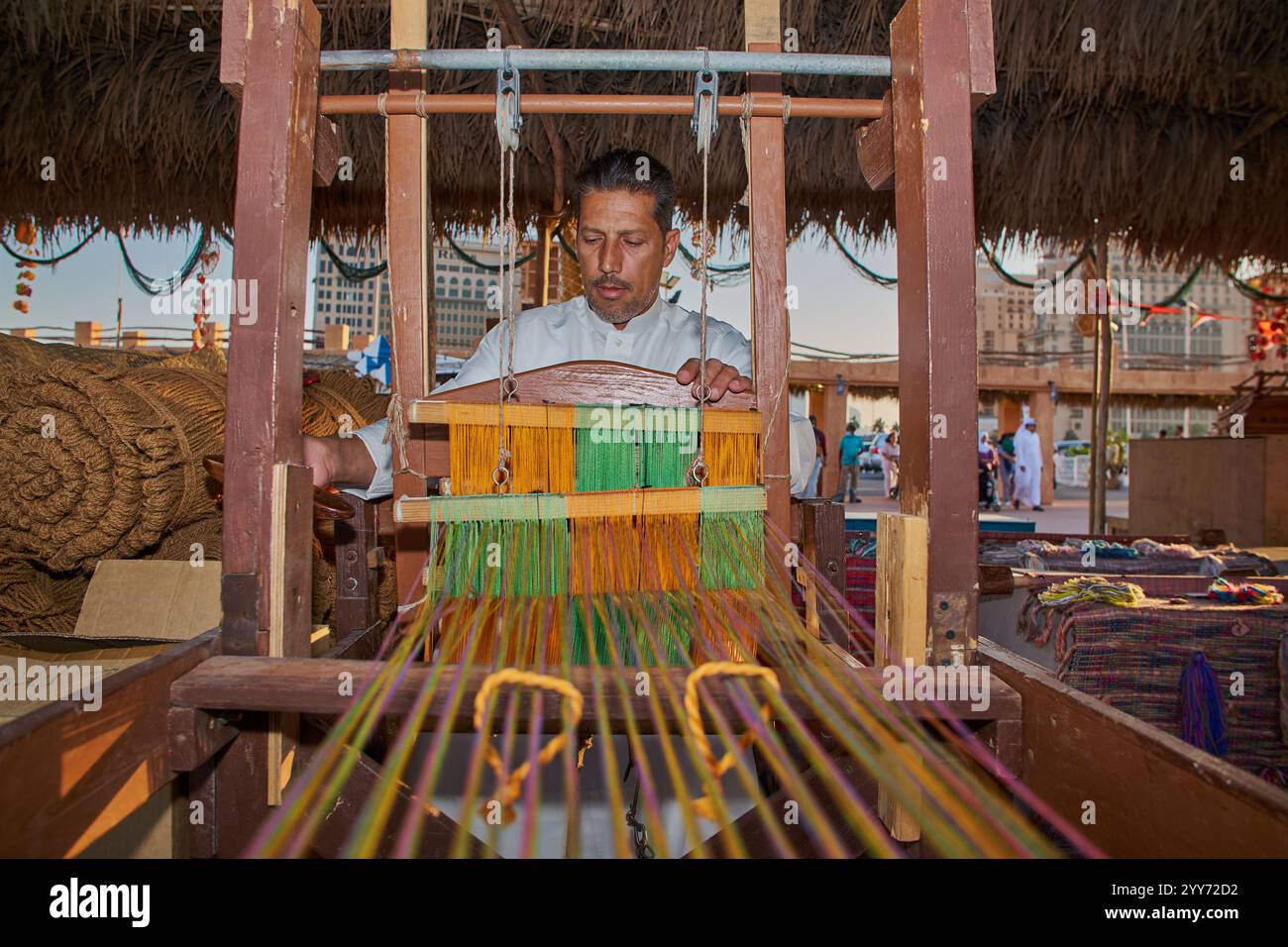 An Arabic craftsman working on traditional wooden loom weaving with ...