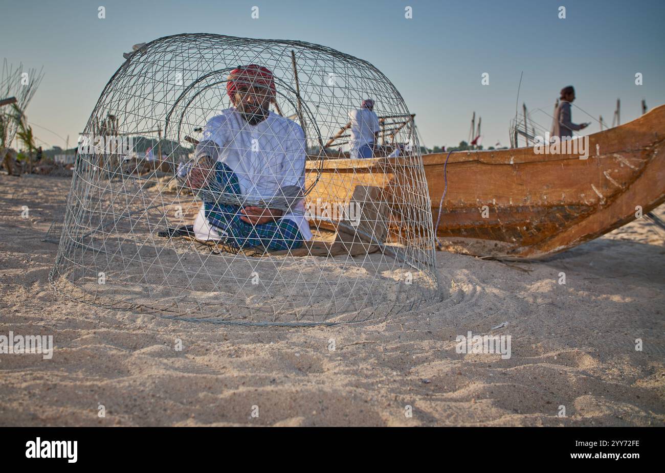 An Arabic craftsman sitting on the beach and making a fishing net in ...