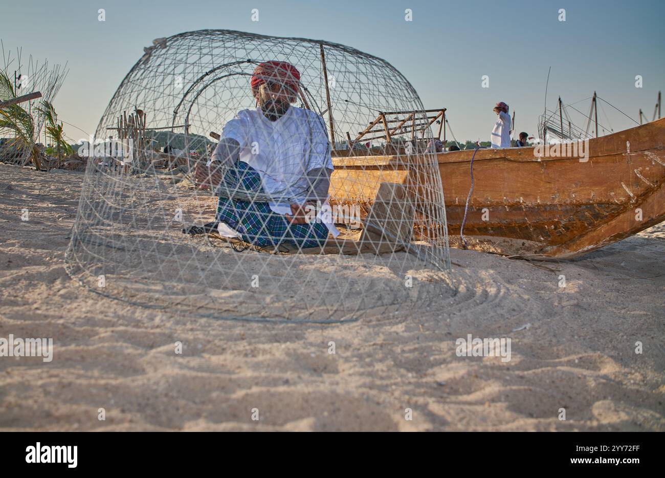 An Arabic craftsman sitting on the beach and making a fishing net in ...