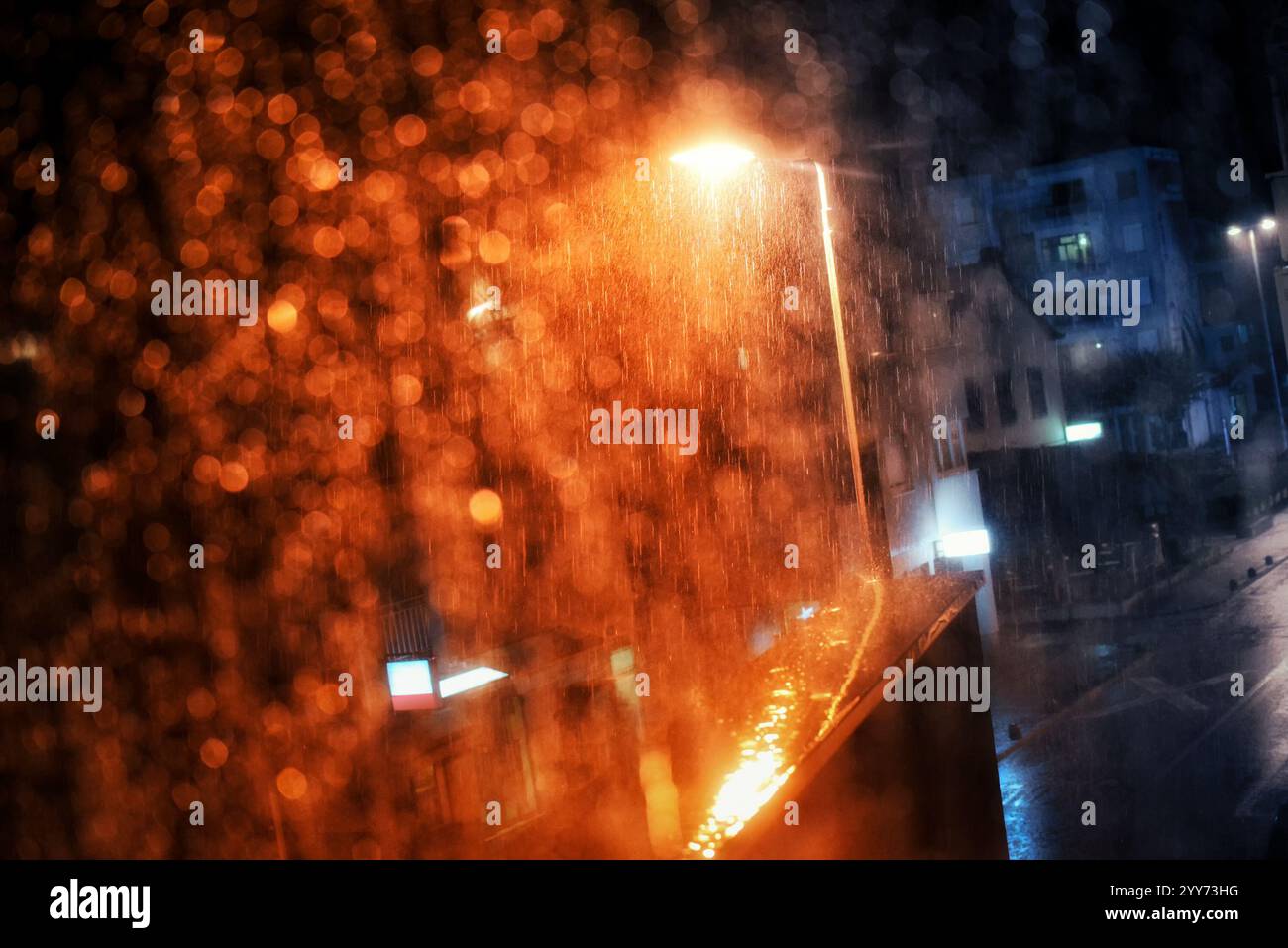 Rain drops on the window with dark streets outside and street lights ...