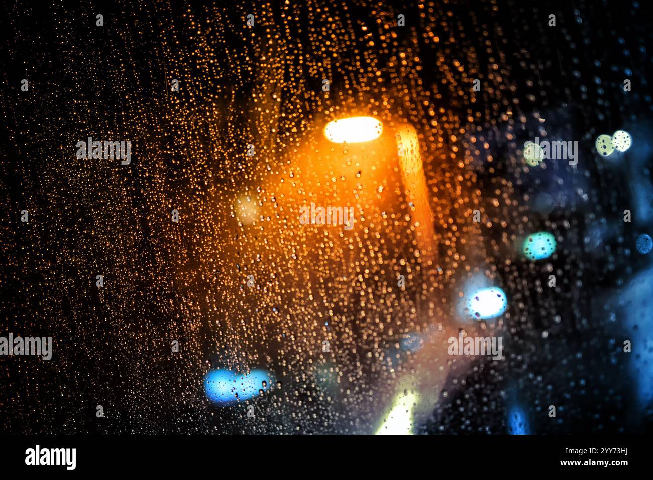 Rain drops on the window with dark streets outside and street lights ...