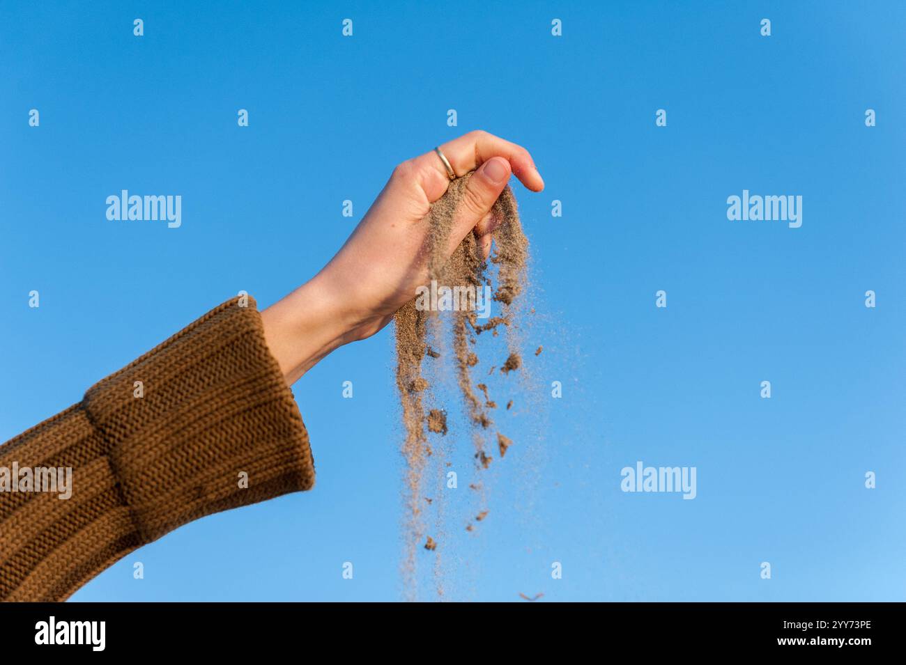 Sand falling from the woman's hand Stock Photo - Alamy