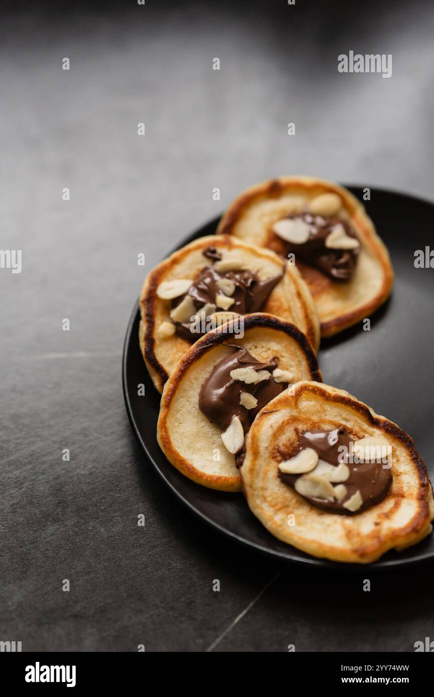 Plate of pancakes dripping with Nutella and almond crumbs with dark ...