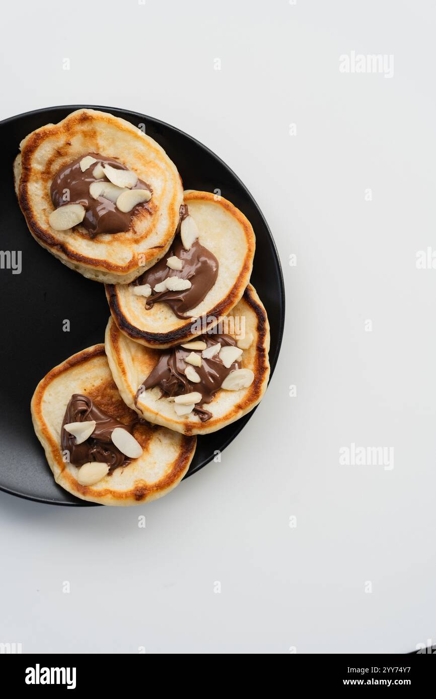 Plate of pancakes dripping with Nutella and almond crumbs with dark ...