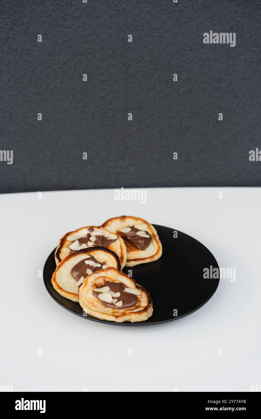 Plate of pancakes dripping with Nutella and almond crumbs with dark ...