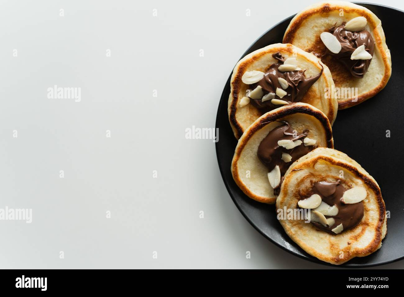 Plate of pancakes dripping with Nutella and almond crumbs with dark ...
